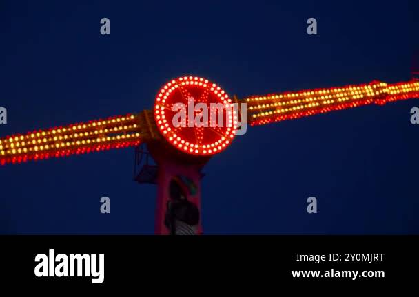 A vibrant amusement ride adorned with glowing lights against the night ...