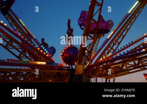 A vibrant amusement ride adorned with glowing lights against the night ...