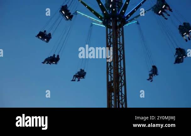 A vibrant amusement ride adorned with glowing lights against the night ...
