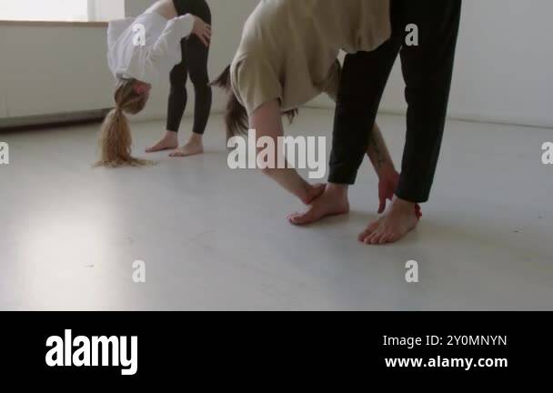 Two dance partners standing barefoot in studio, doing forward fold ...