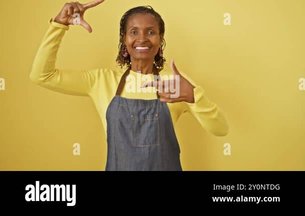 Joyful middle-aged african american woman in apron, making a camera ...