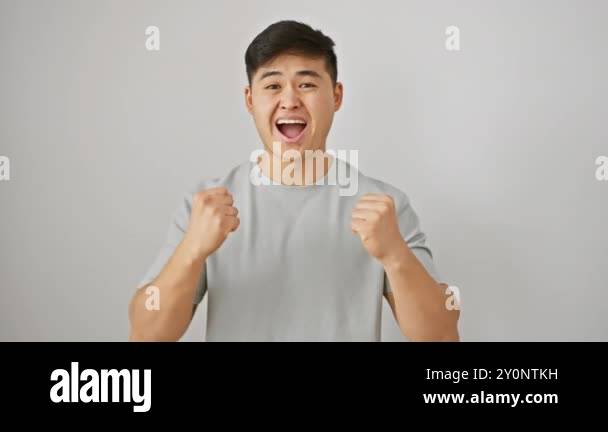 Excited young chinese man, standing proud in a t-shirt, arms raised in ...