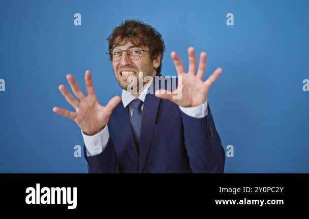 Terrified young man in business suit shouting in fear, hands displaying ...