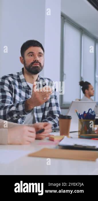 Vertical screen: Colleagues shaking hands during office meeting with ...