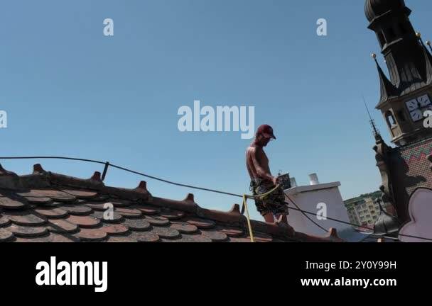 The roof worker repairs the roof. Roof worker with safety rope and ...
