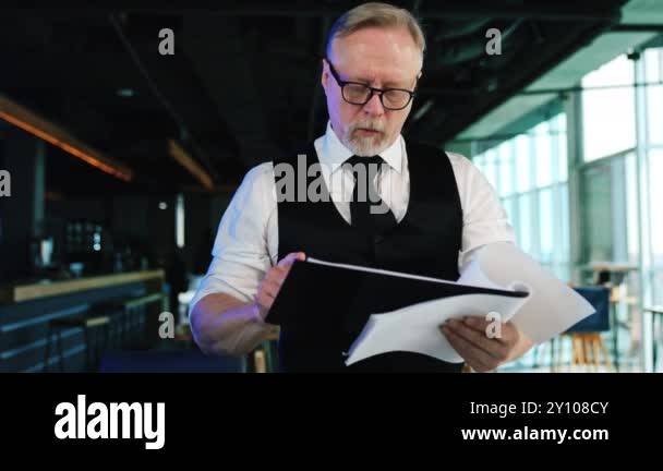 Focused male businessman wearing white shirt and black vest holding ...