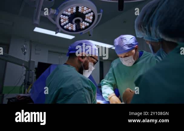 Surgical team working in the operational theatre. Doctor uses sponge on ...