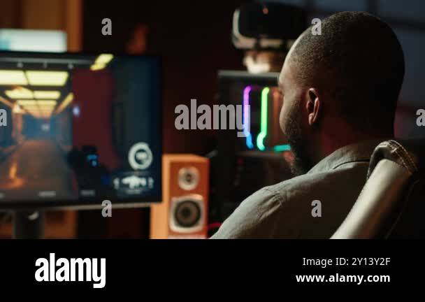 Man in neon lit apartment playing immersive video games on gaming PC at ...