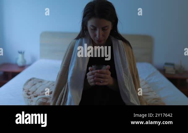 A person with a fever is seen resting in bed at night, feeling sick and ...