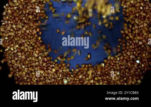 Golden brown buckwheat grains are captured in motion as they cascade ...
