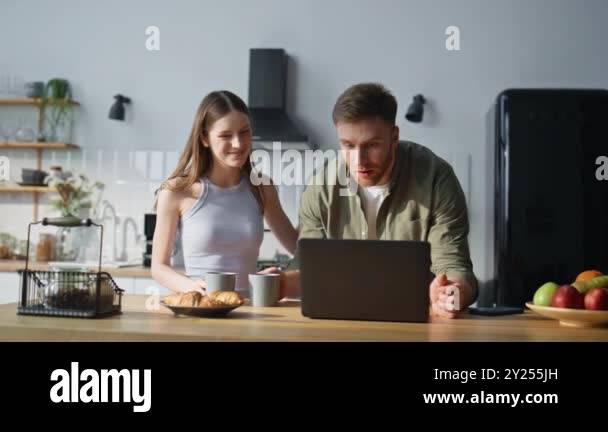 Husband kissing goodbye with wife bringing coffee cup at home kitchen ...