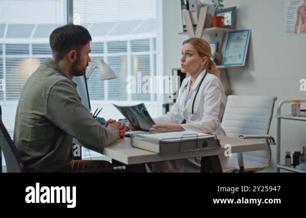 Serious therapist talking results showing x-ray. Doctor consulting ...