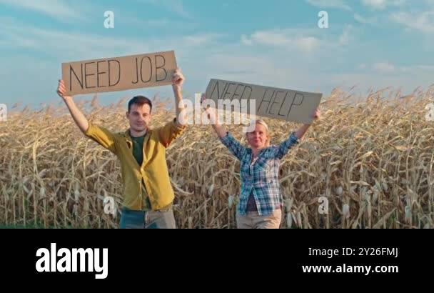 Two farmers stand side by side against a cornfield backdrop, holding ...