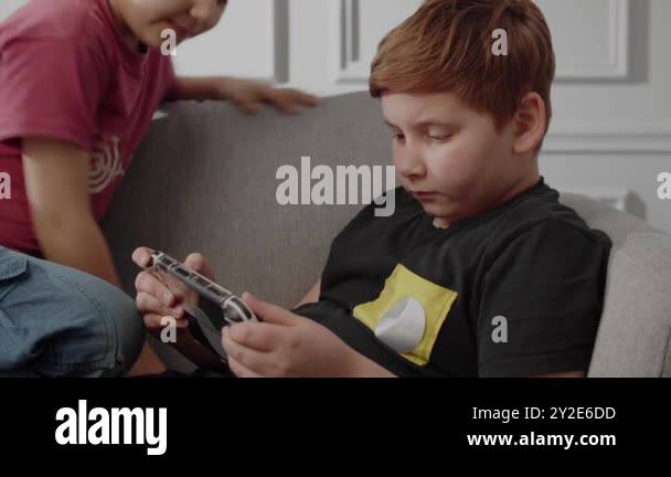 Younger brother waiting for his turn to play computer games. Boy ...