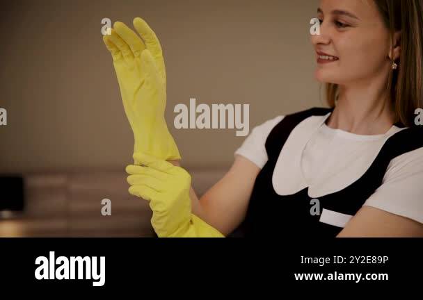 Close up of woman maid putting on yellow rubber gloves. Professional ...
