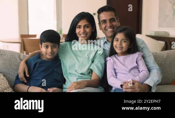 Happy young Indian mom and dad holding little daughter in arms on lap ...