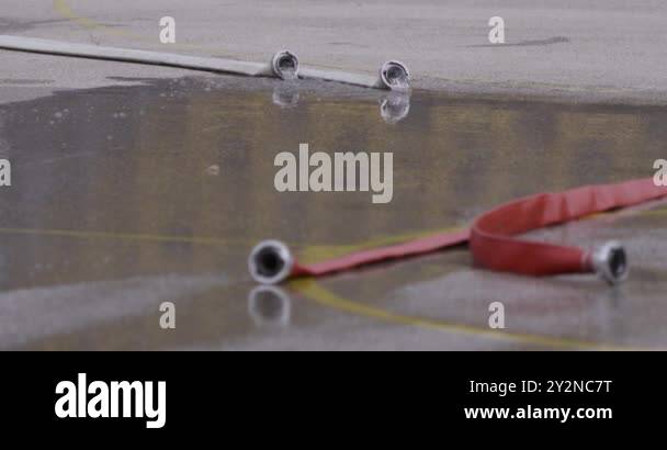 An up-close shot captures a fire hose with a powerful stream of water ...