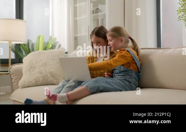 Carefree Caucasian kids daughters family girls watching movie funny cartoon on laptop computer ...