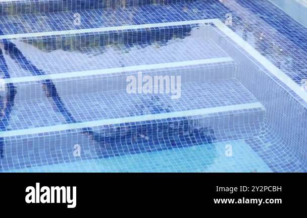 Clear water reveals submerged steps leading into a blue-tiled swimming ...