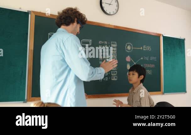 Asian boy finish writing answer while teacher clapping hands to ...