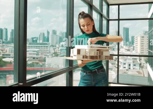 Young happy beautiful engineer check house model by turning left side ...