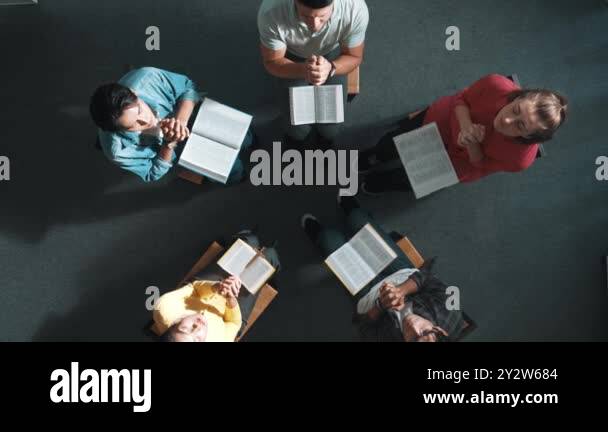 Top down view of prayers reading bible with cross on the laps while ...