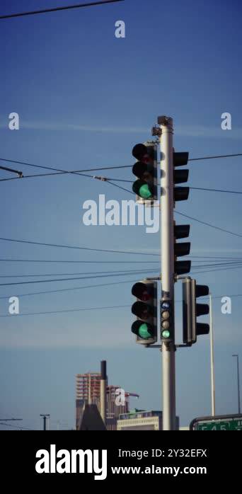 A tall traffic light pole stands under a clear blue sky in an urban ...