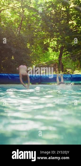 Two kids dive into a swimming pool, creating splashes as they plunge ...
