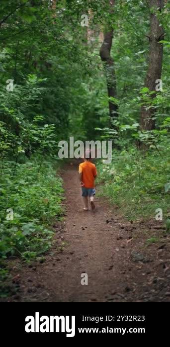 Rear view of a baby running barefoot by the path in the forest. Child ...