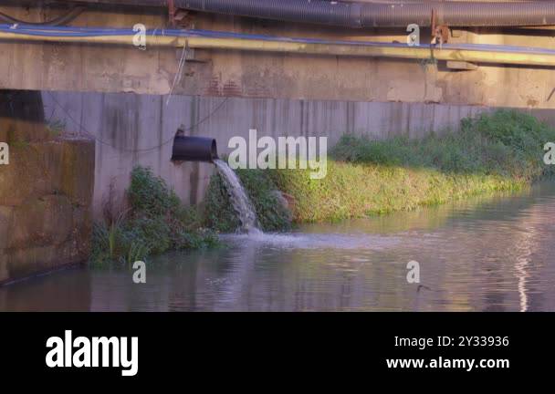 Wastewater pours from pipe into river beneath bridge, creating murky ...