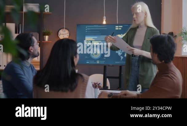 Young businesswoman making presentation speaking to colleagues handing ...