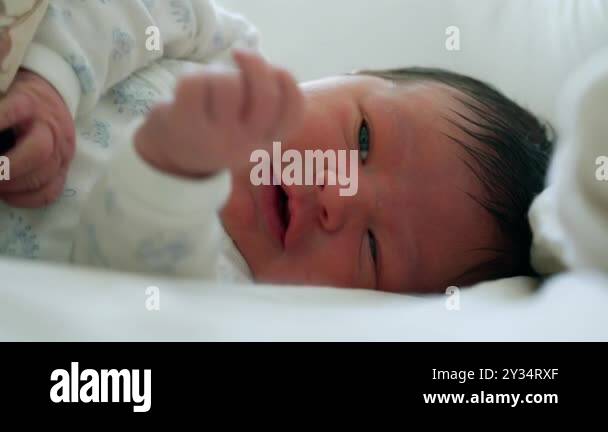 Newborn baby grimacing with eyes open, showing early expressions and ...