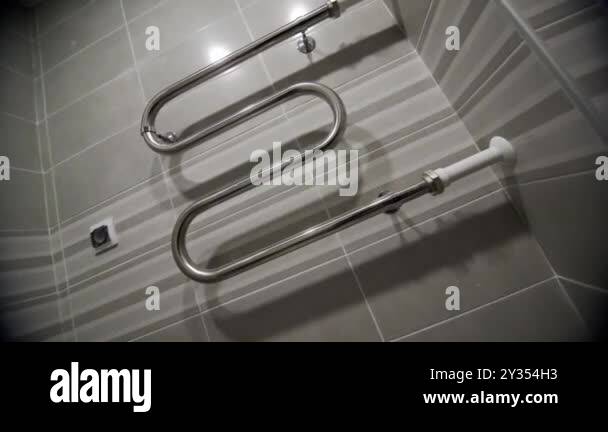 Towel rack on tiled wall near toilet bowl in bathroom closeup. Radiator ...