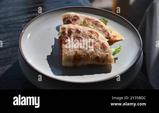 A flatbread stuffed with fish and cheese is rotated on a round table ...