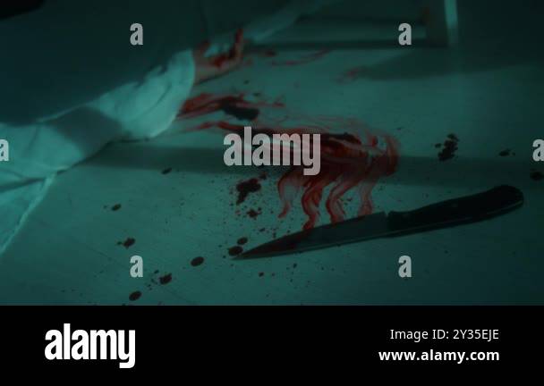 Close up view of knife lying on floor with blood splattered near body ...