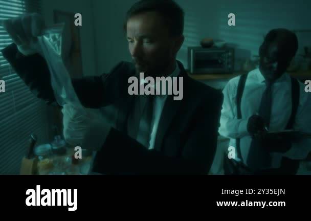 Detective in formal suit and gloves inspecting evidence in plastic bag ...