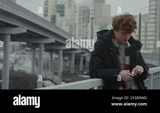 Melancholic young man pulling cigarette out of pack, lighting it and ...