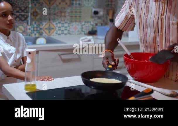African American father man hand frying pancakes together with daughter ...