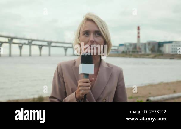 Waist up of Caucasian female reporter standing by waterfront with ...