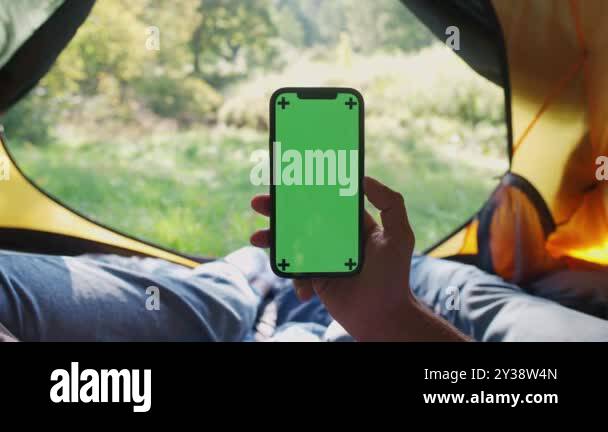 Handheld, first-person view, man holding a smartphone with a green ...