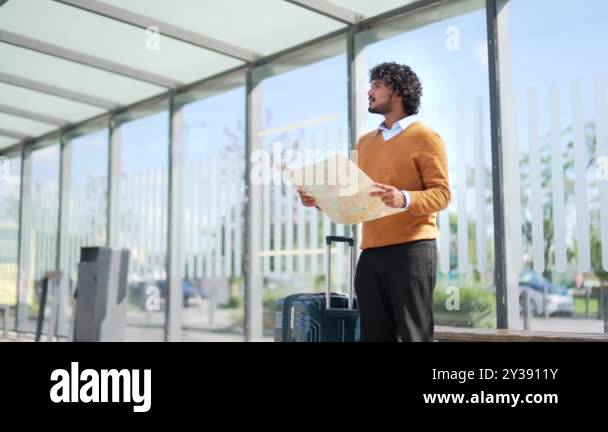 Man at bus stop looking at map, planning travel. Appears confident male ...