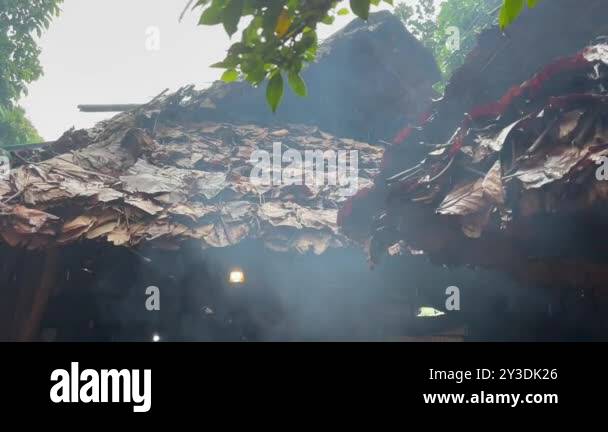 Typical leaf roof of the Karen tribe on a rainy day as smoke rises from ...
