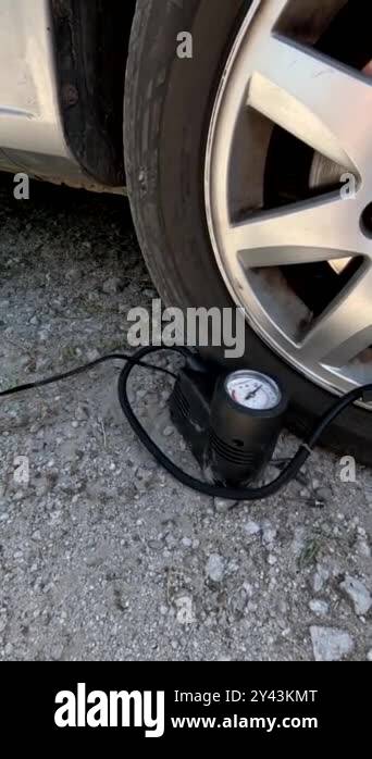 A man inflates a car wheel with a compressor. Close-up of a small car ...