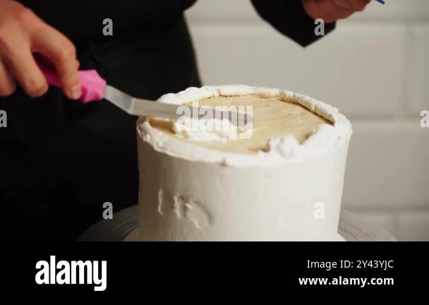 The process of leveling the sides of a cake. The pastry chef applies ...