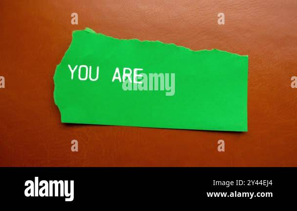 You are stronger than you think message writing on ripped green torn paper piece on a brown ...