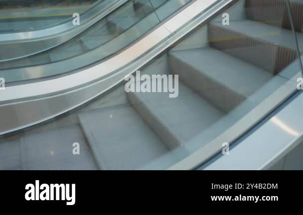 Modern escalator with glass railings leading upwards in public space ...