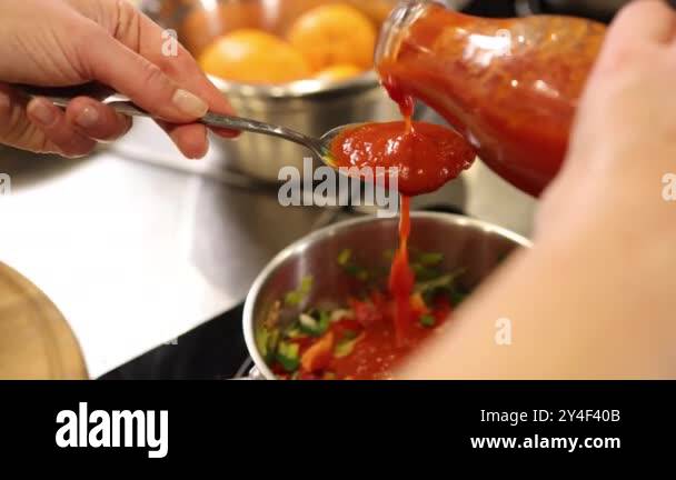 Tomato sauce, Sauteed sauce, Stovetop cooking. Hand is pouring tomato ...