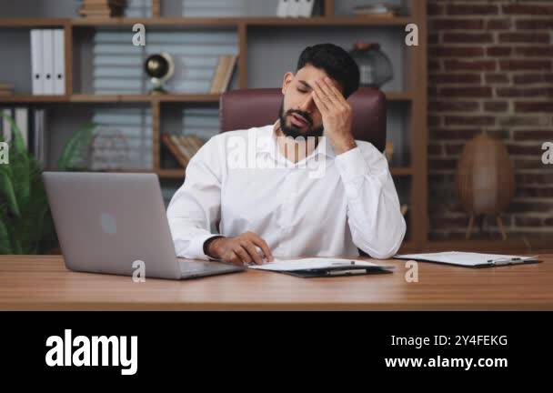 Tired hindu male feeling headache and massaging temples during working ...