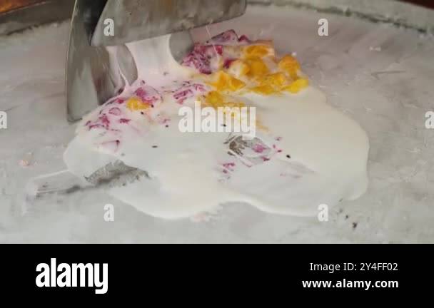 Making rolled ice cream with mixed dragon fruits and mango on a cold ...