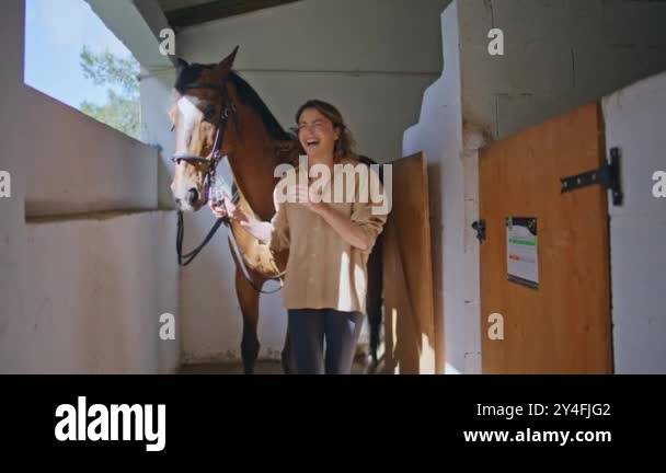 Laughing equestrienne having fun with horse at farm paddock. Happy ...